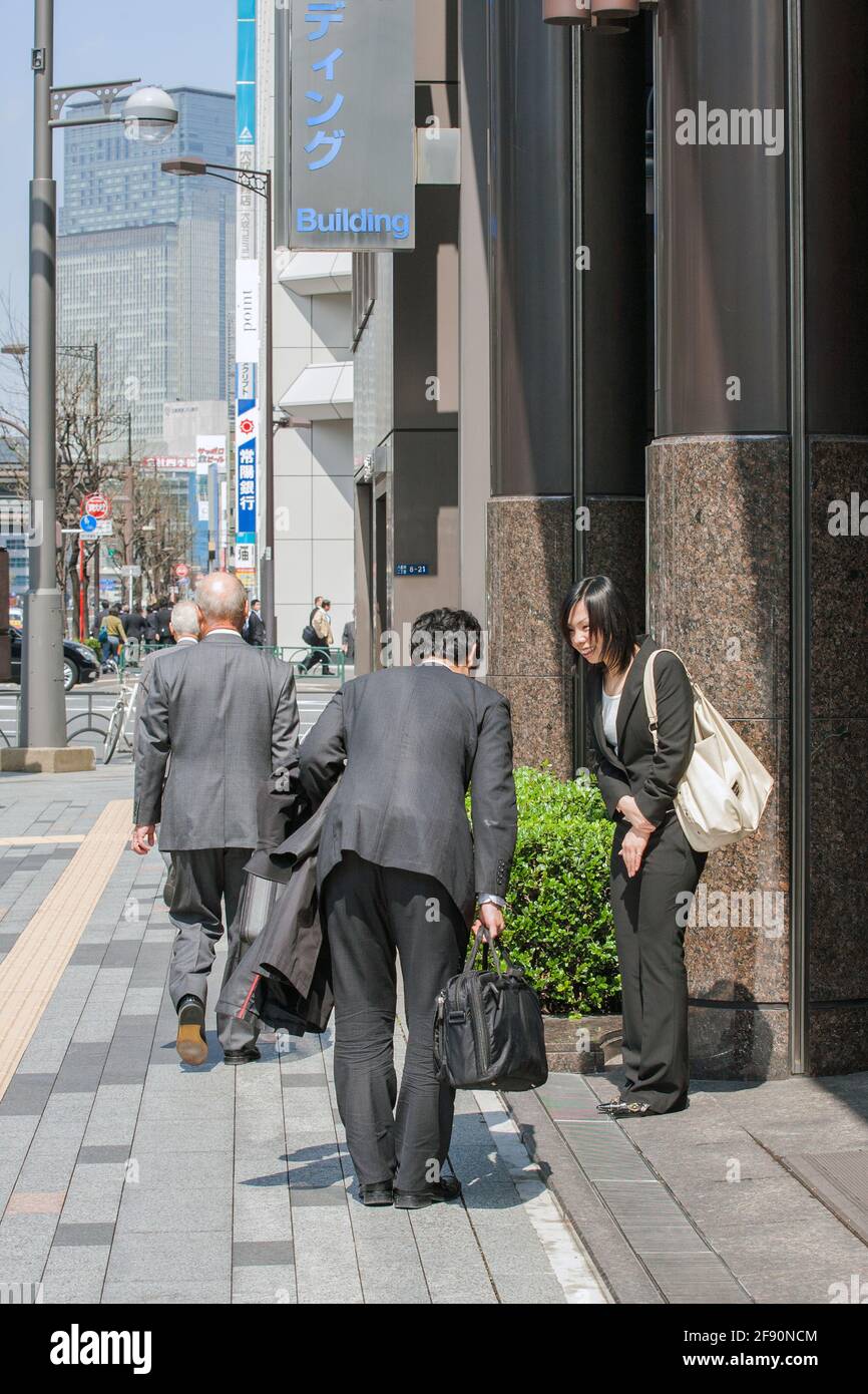 Japanese male and female office workers bowing (ojigi) with each other ...