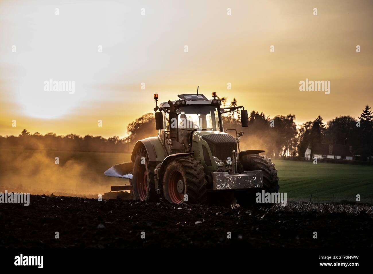Ploughing a field at sunset with a tractor and plough, ready for crops ...