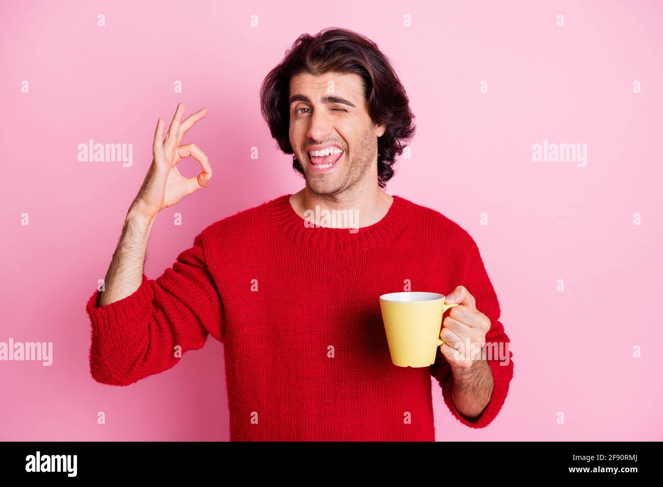 Portrait of nice glad flirty cheerful guy drinking tea showing ok-sign ...