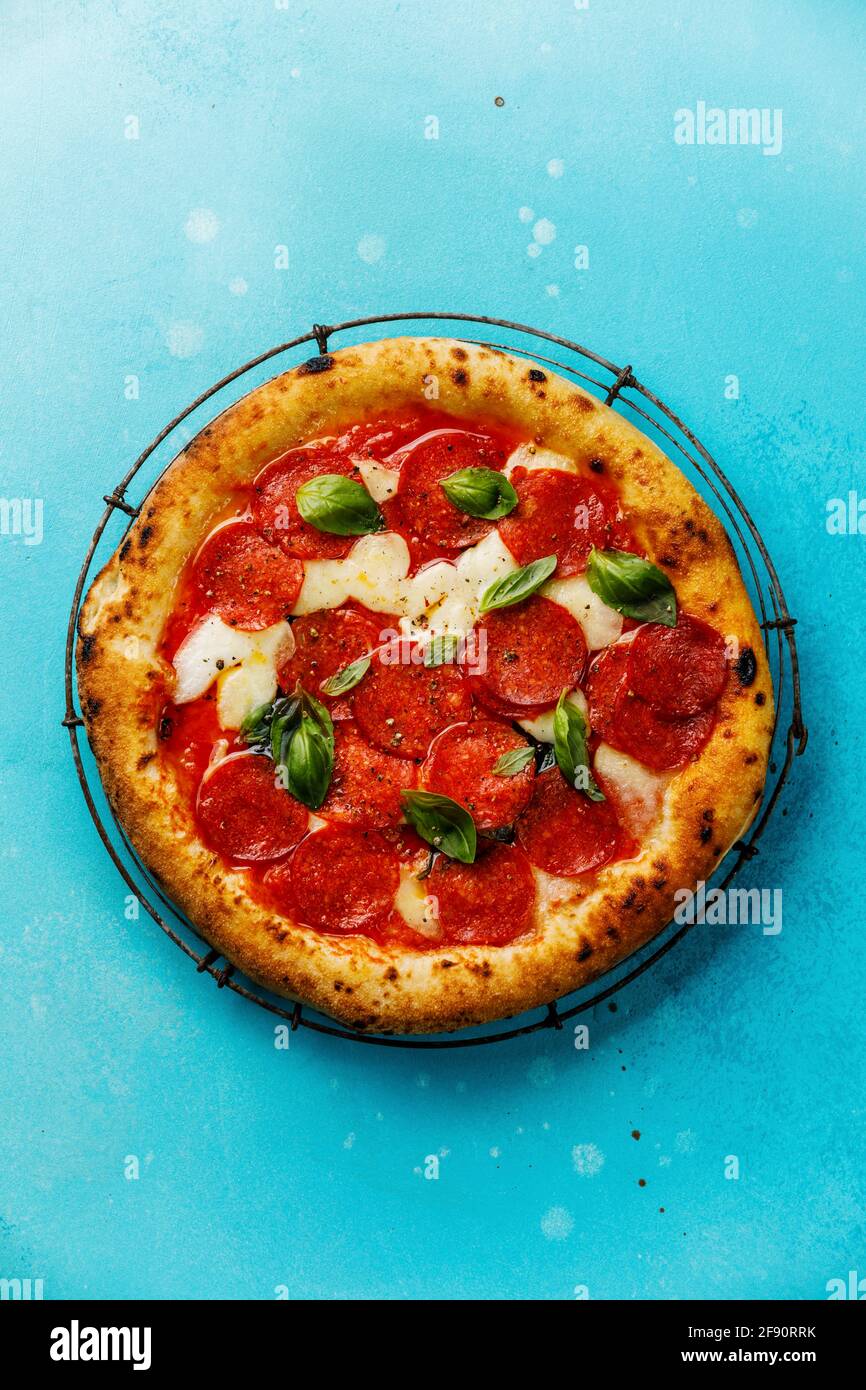 Pepperoni Pizza on cooling rack on blue background Stock Photo - Alamy