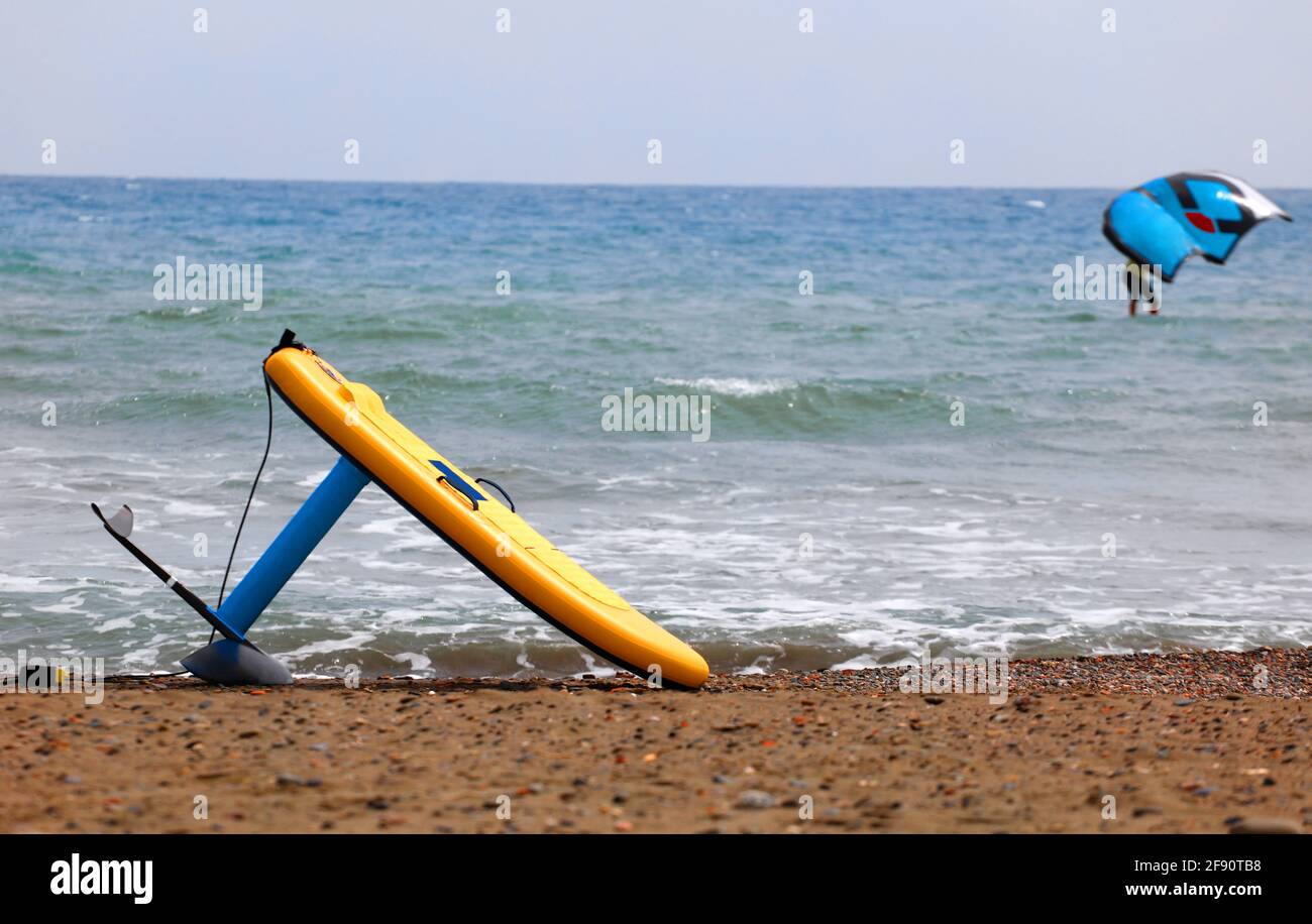 wind-foil board on the sand, in the background sea with white wavesl ...
