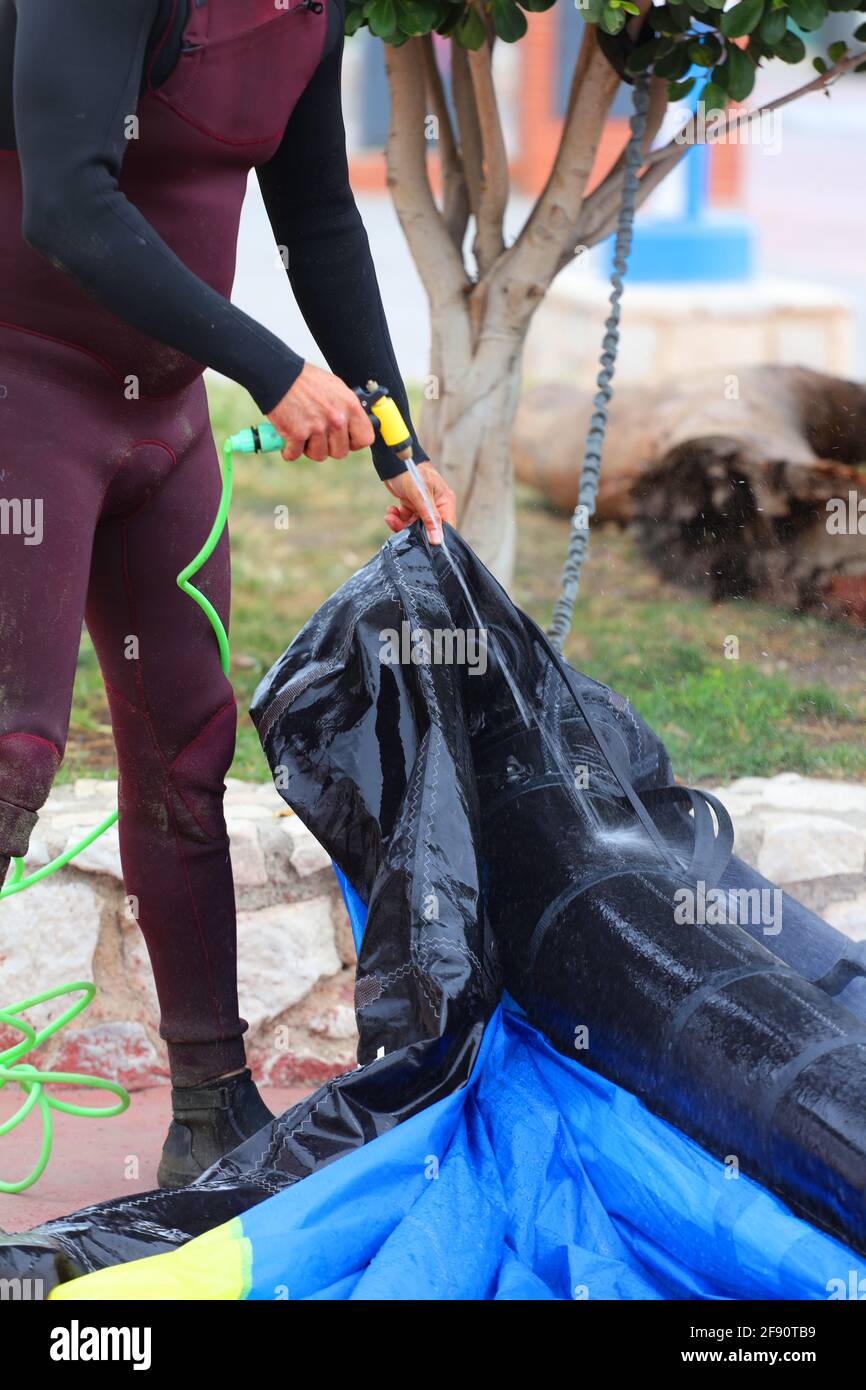 black rider helmet cleaning with water hose, kite windfoil background ...