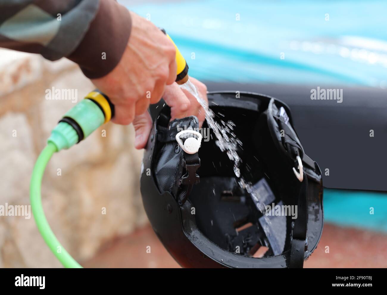 black rider helmet cleaning with water hose, kite windfoil background ...