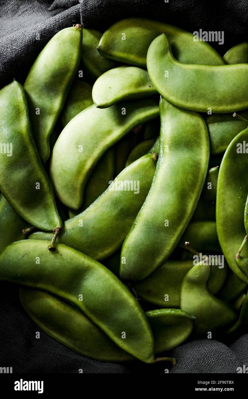 Lima beans pods sitting in a dark grey linen Stock Photo - Alamy