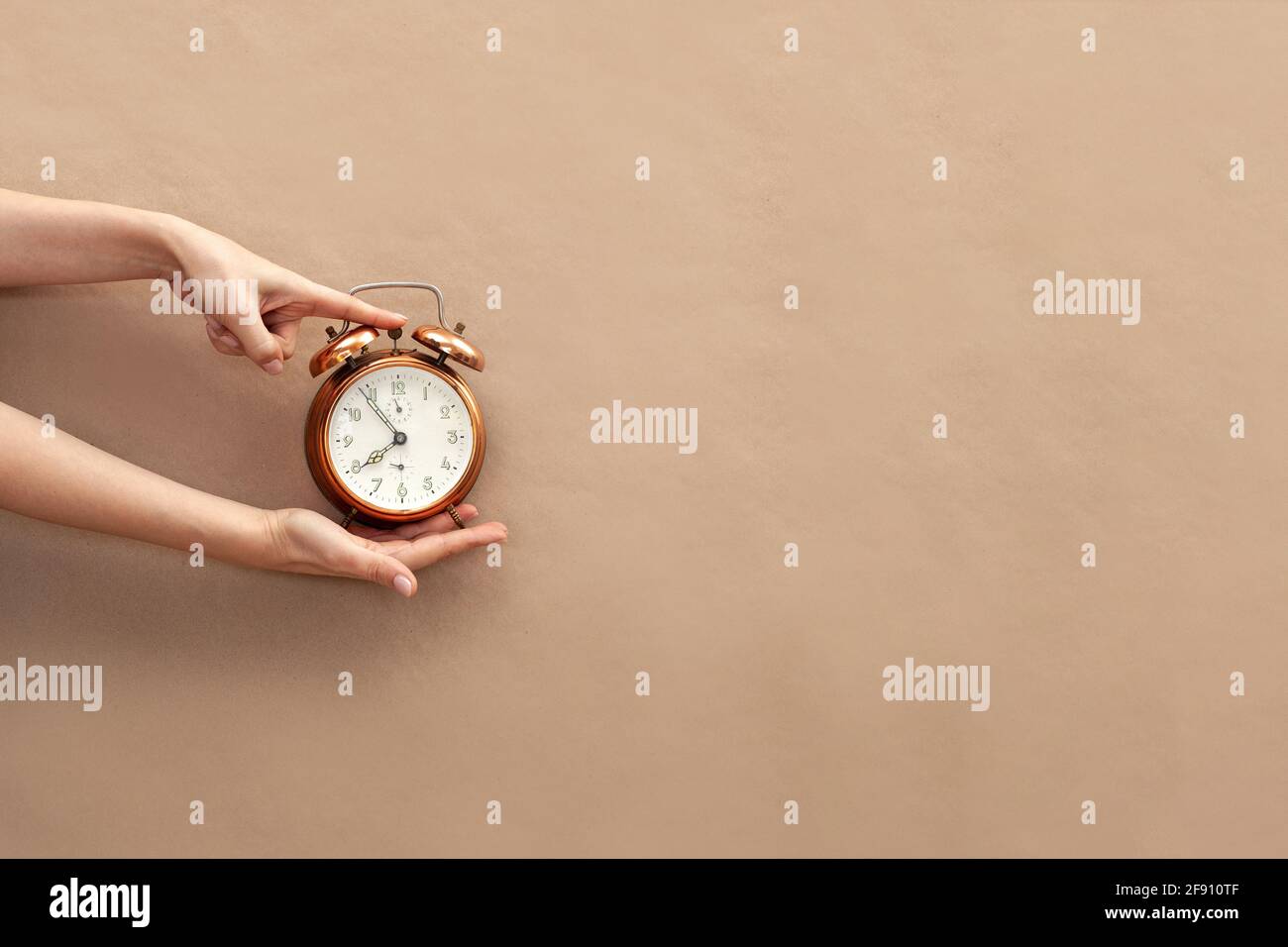 Hand holding bronze watch on brown paper background Stock Photo - Alamy