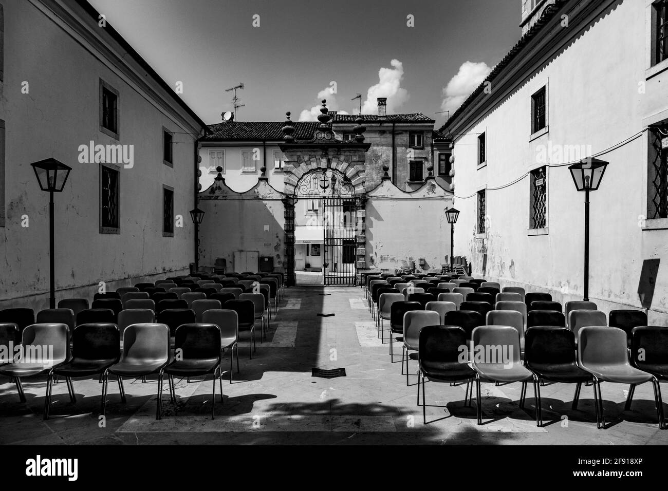 Black and white shot of a yard between nice buildings with empty chairs ...