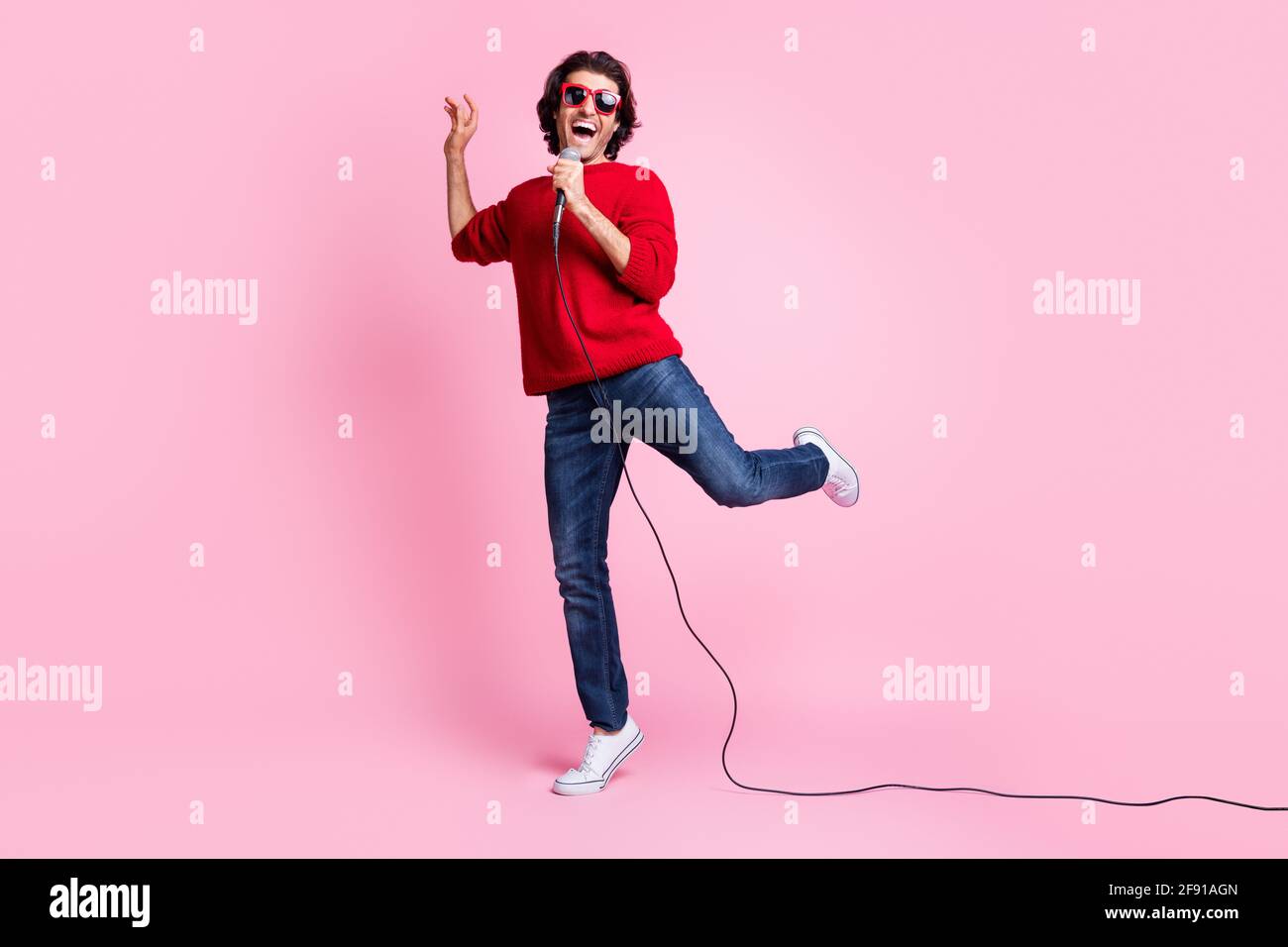 Photo portrait of man singing standing on one leg holding mic in hand ...