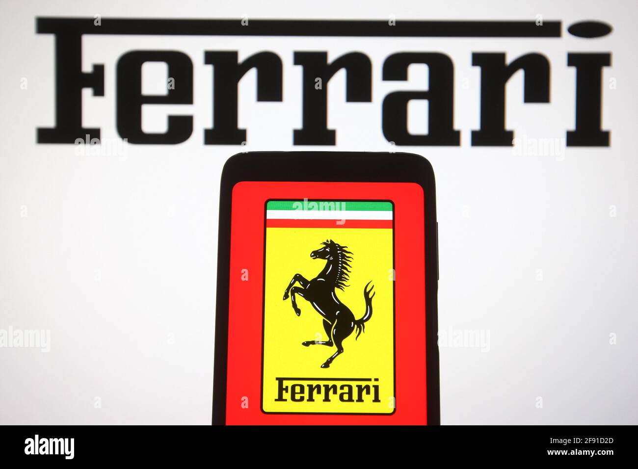 In this photo illustration a Ferrari logo is seen on a smartphone and a ...