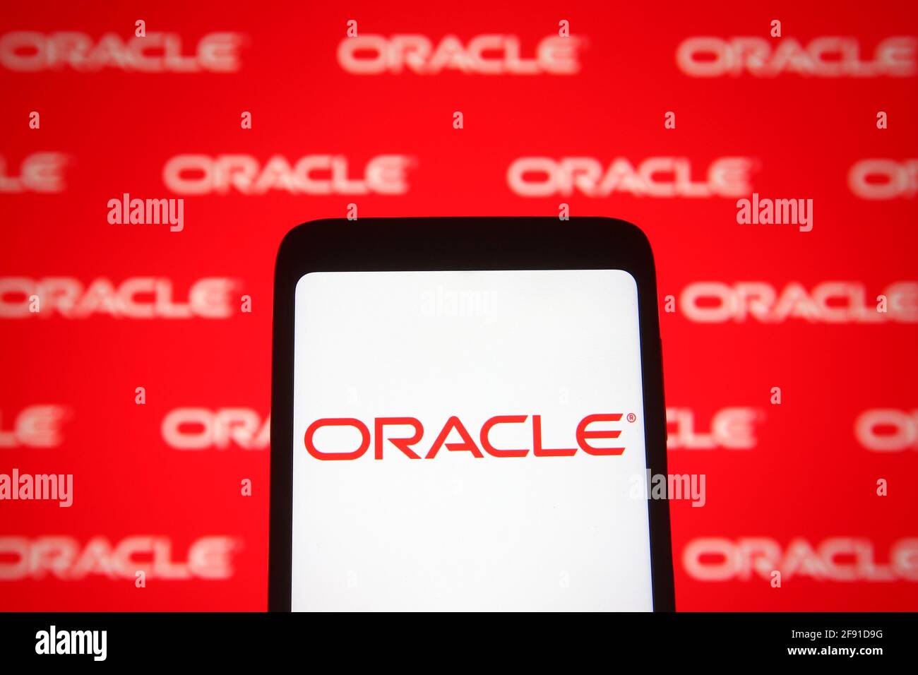 In this photo illustration an Oracle logo is seen on a smartphone and a ...