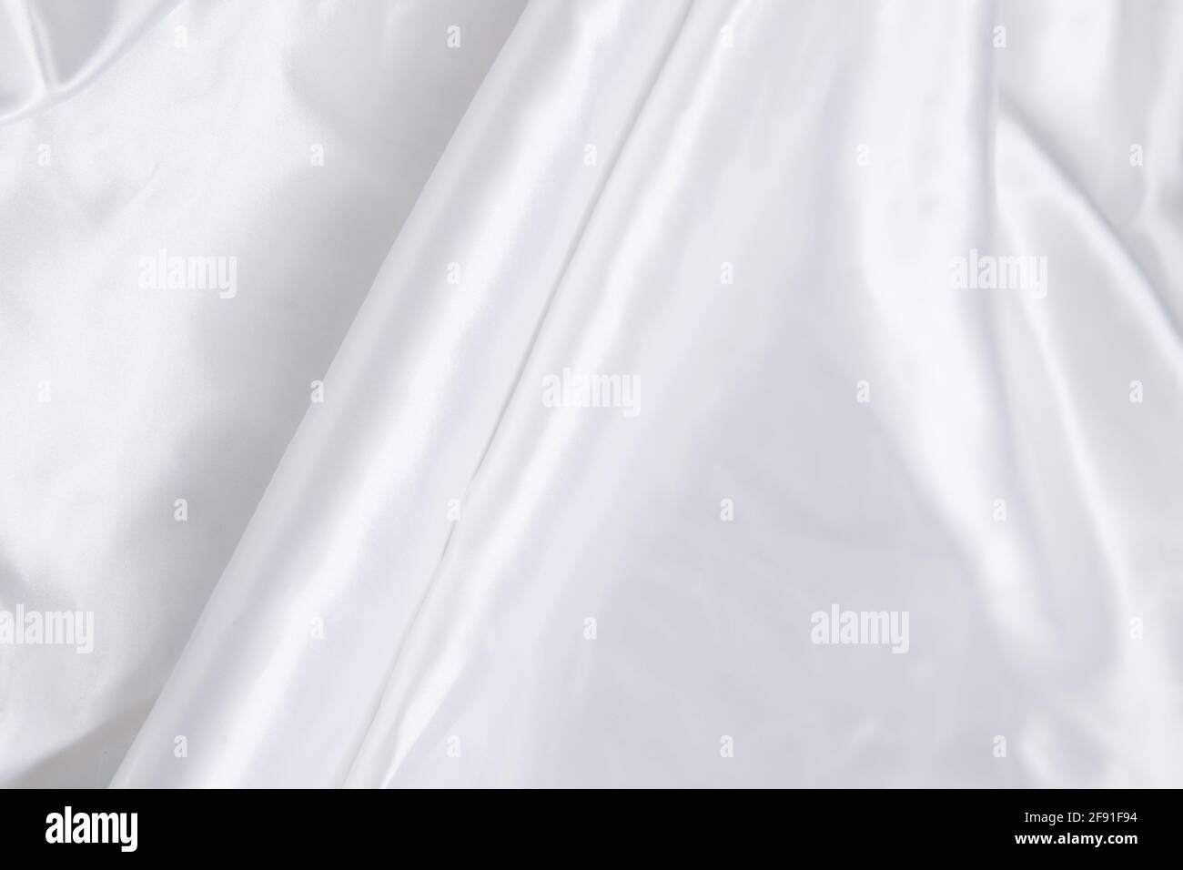Colored white textile satin fabric folded in folds and waves with ...