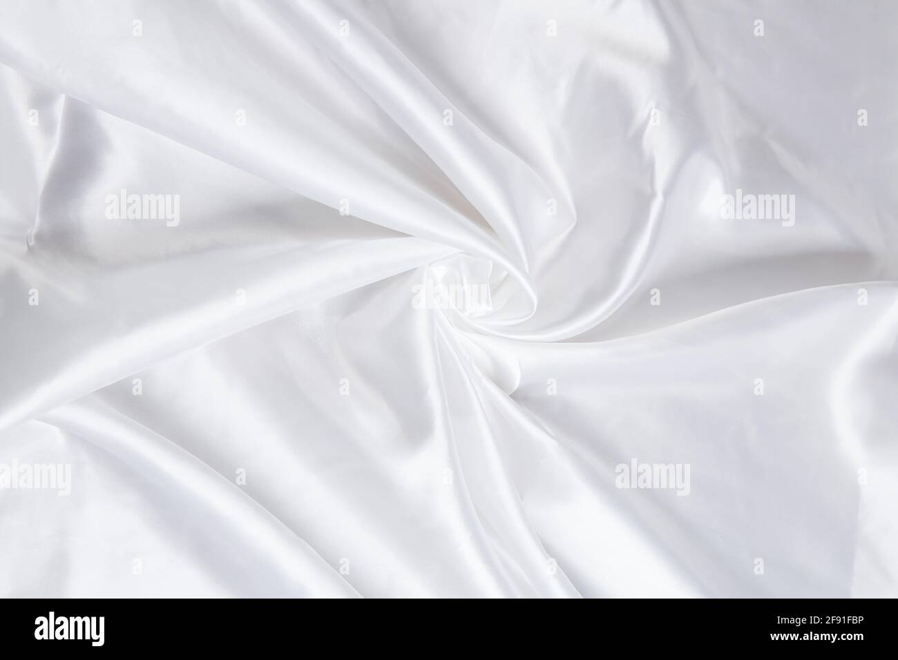 Colored white textile satin fabric folded in folds and waves with ...
