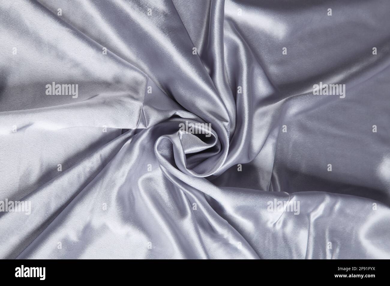 Colored silver textile satin fabric folded in folds and waves with ...