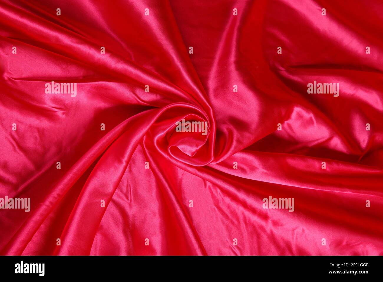 Colored red textile satin fabric folded in folds and waves with ...