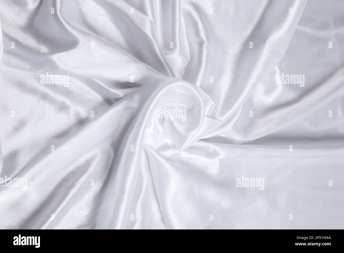 Colored white textile satin fabric folded in folds and waves with ...