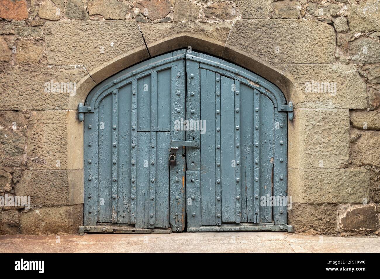 Ancient stone wall with a gate in the old castle. Wooden gate of a ...