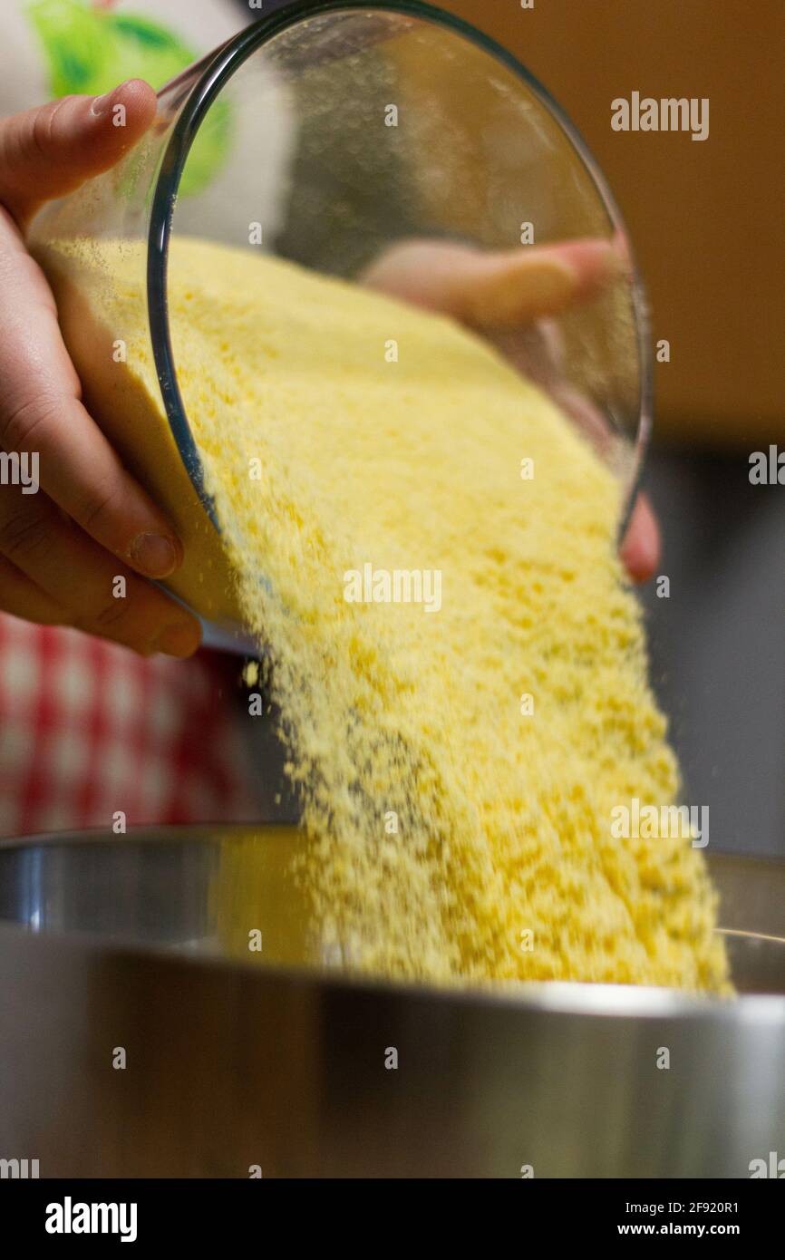 Closeup of a baker pouring yellow flour into a bowl of pastry ...