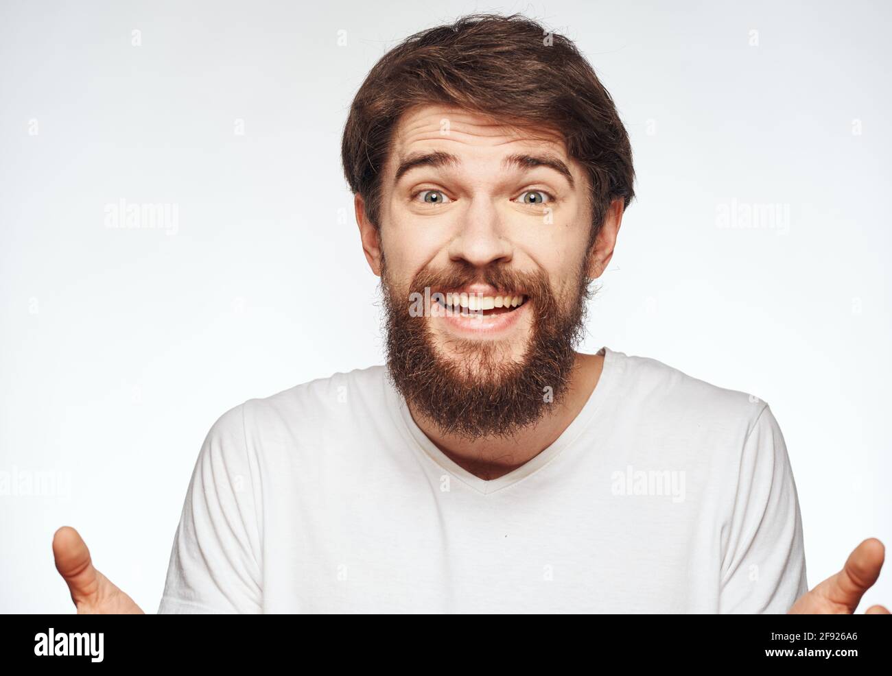 Portrait of an energetic man in a white t-shirt on a light background ...