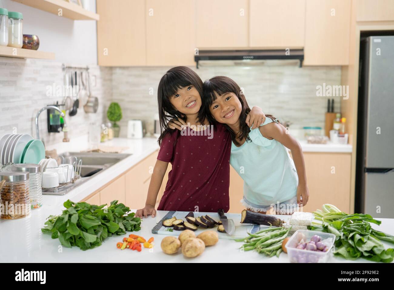 two beautiful little girl preparing and cooking dinner in the kitchen ...