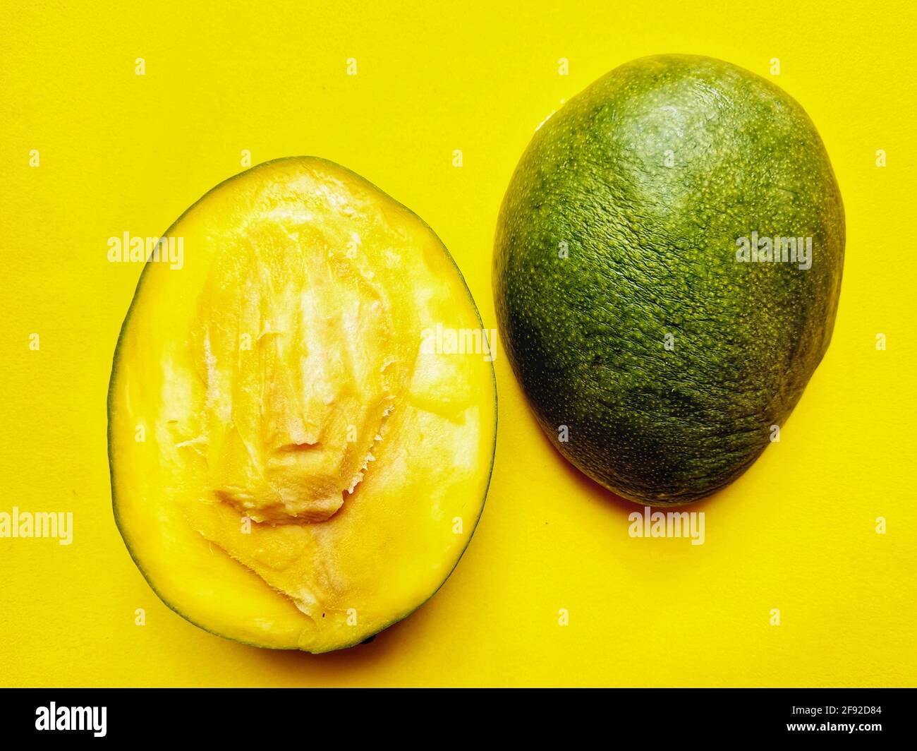 Ripe mango cut in half on yellow background Stock Photo - Alamy