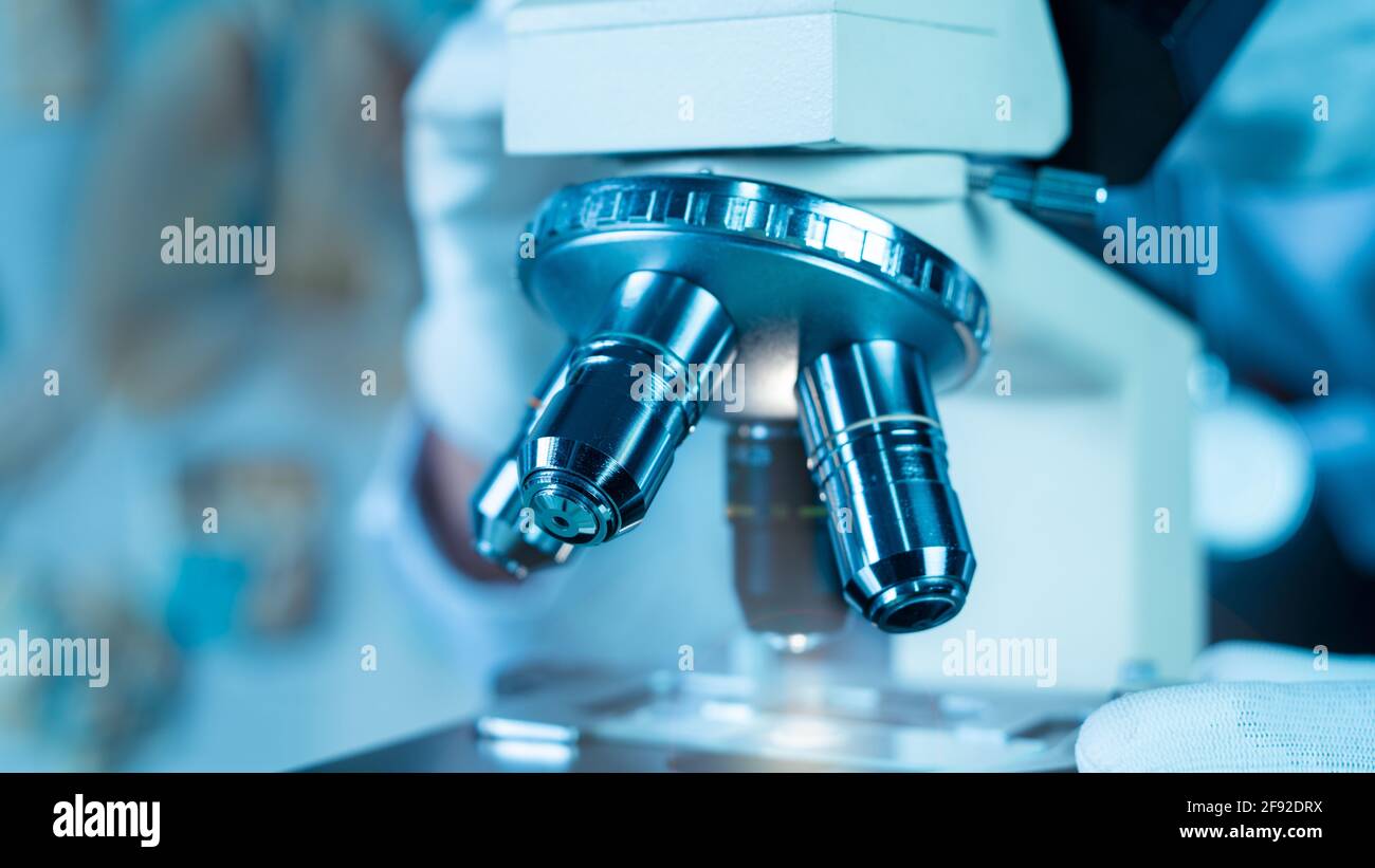 Doctor looking in microscope while working on medical research covid-19 ...