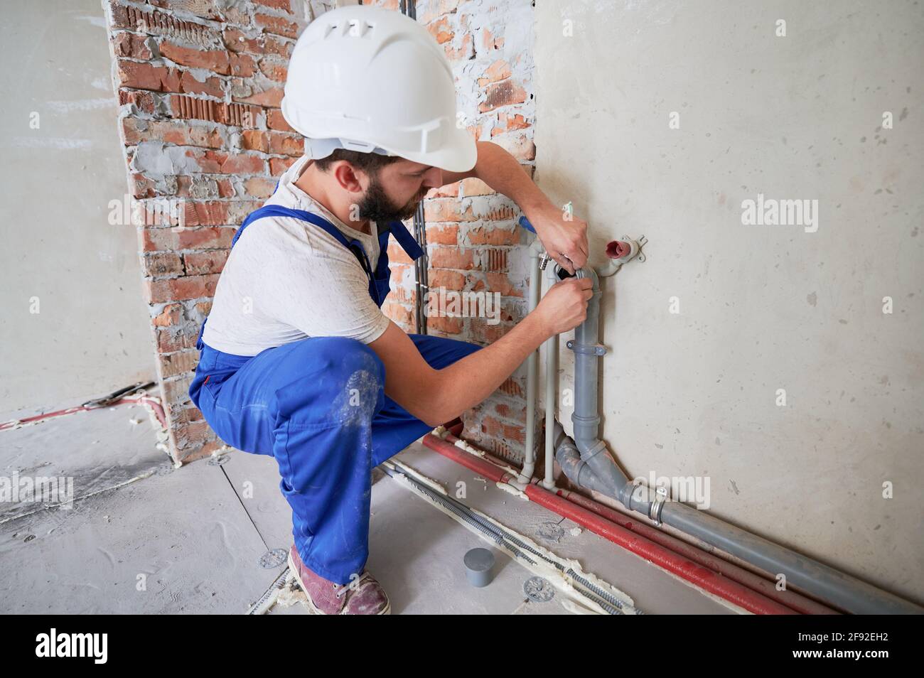 Man in safety helmet lubricating water pipe to reduce friction and ...
