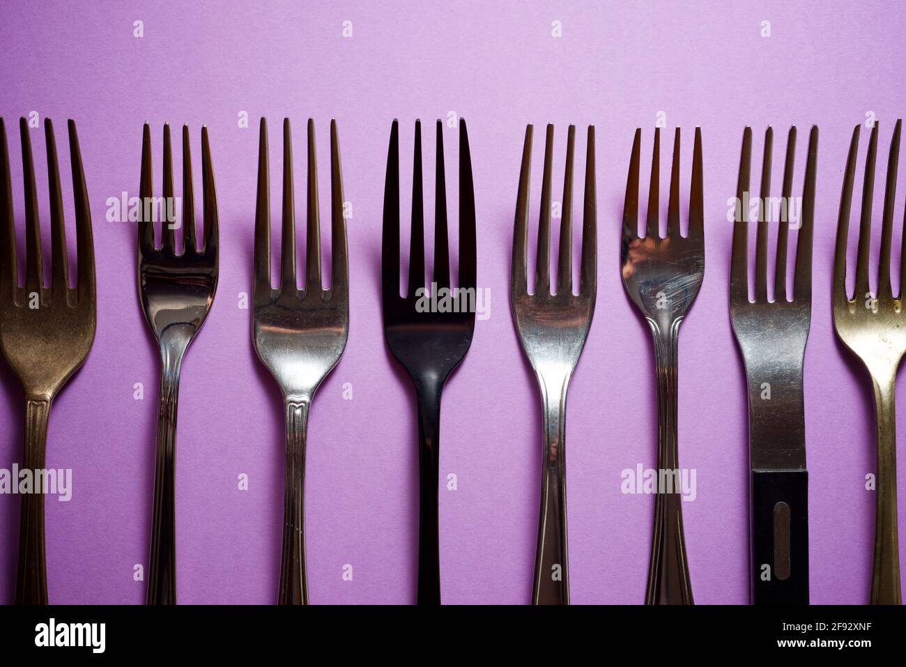 Collection of forks on a purple table Stock Photo - Alamy