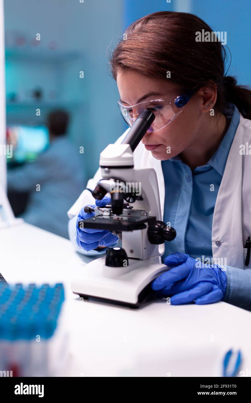 Healthcare scientist looking through microscope in pharmacy lab ...