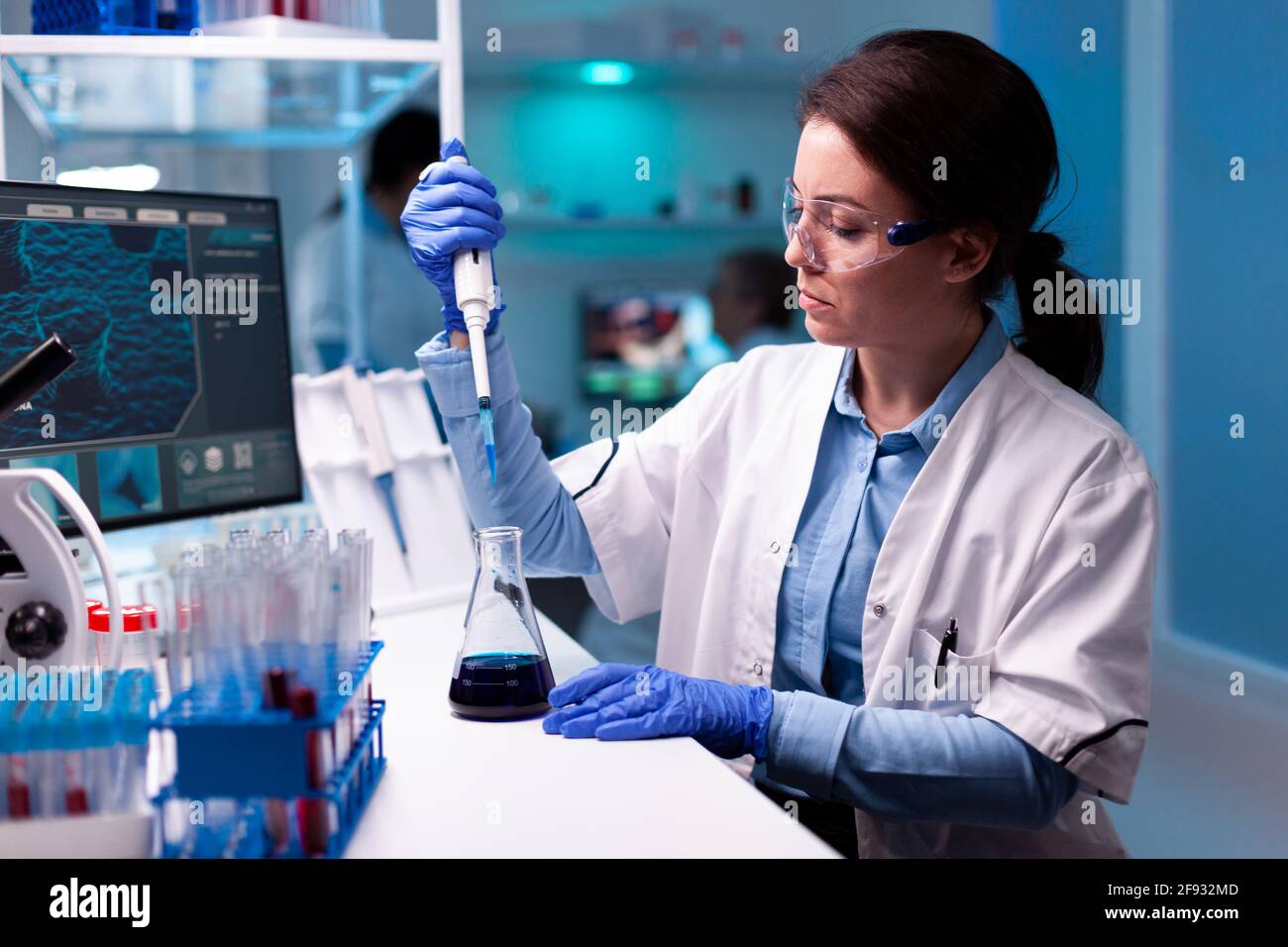 Scientist taking sample with micropipette wearing glasses in modern ...