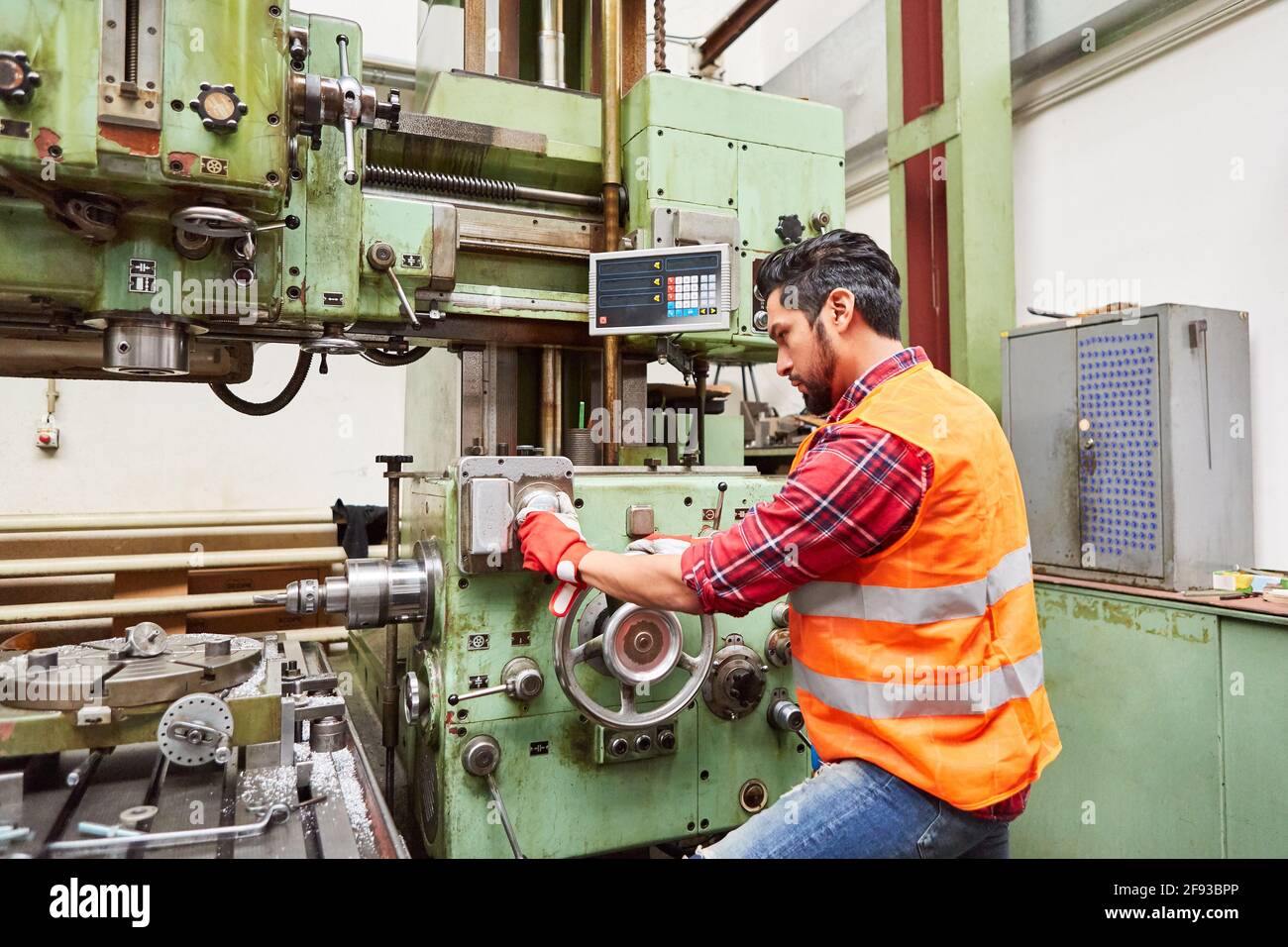 A worker as a machinist operates the coordinate drilling machine in the ...