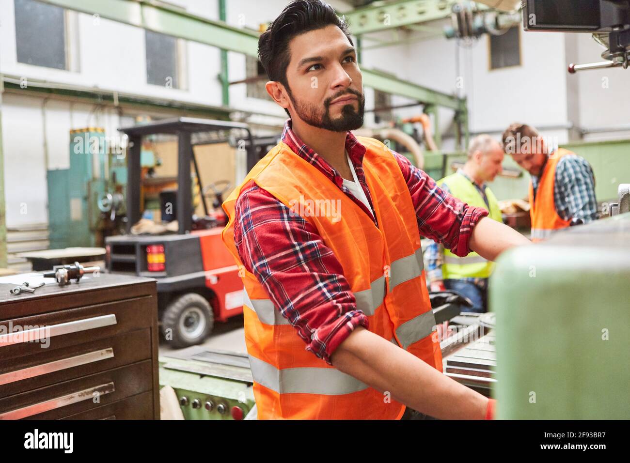 Metal worker in the production of the metal factory operates a machine ...
