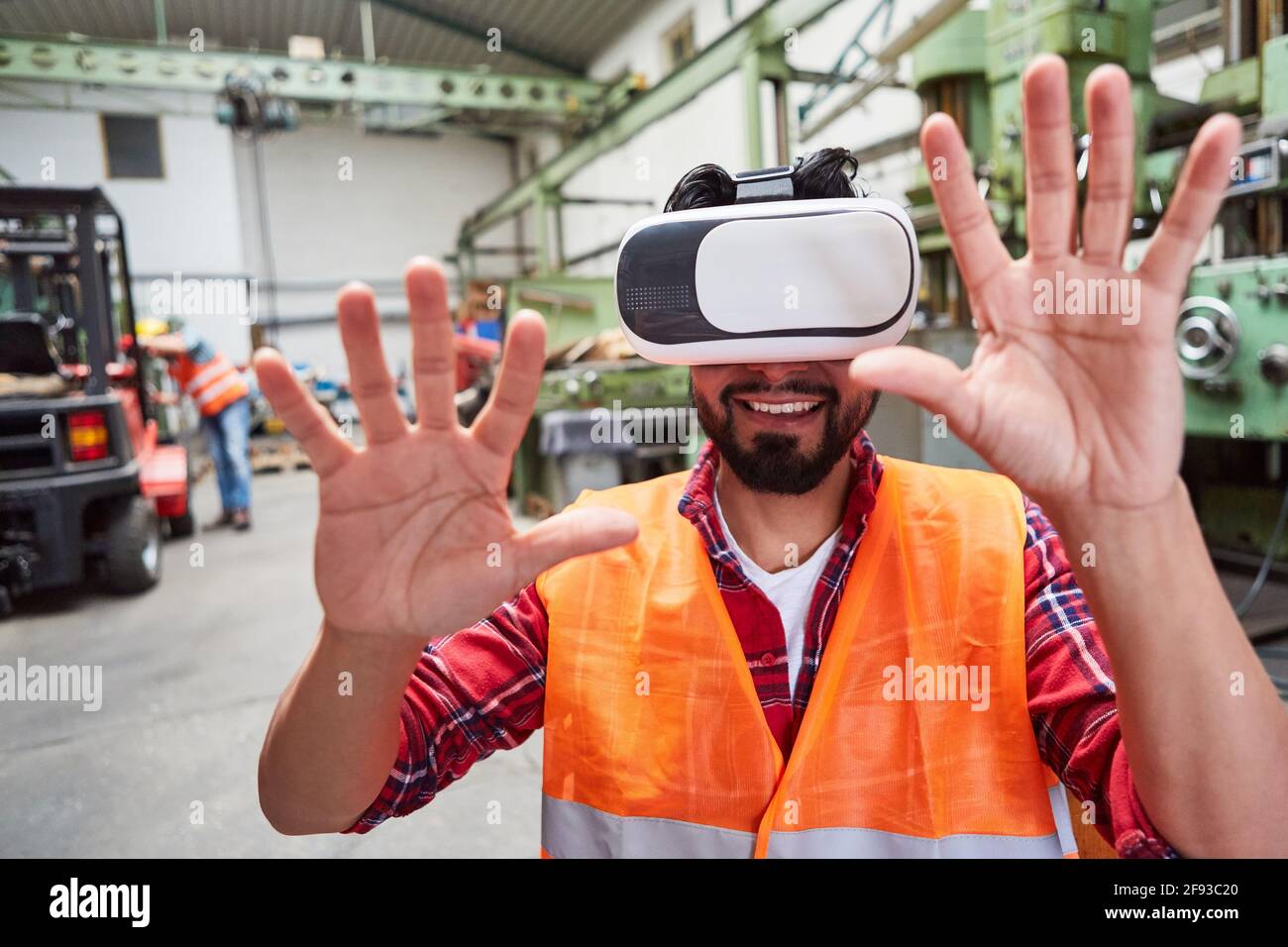 Worker with VR glasses reaches for a virtual reality factory simulation ...