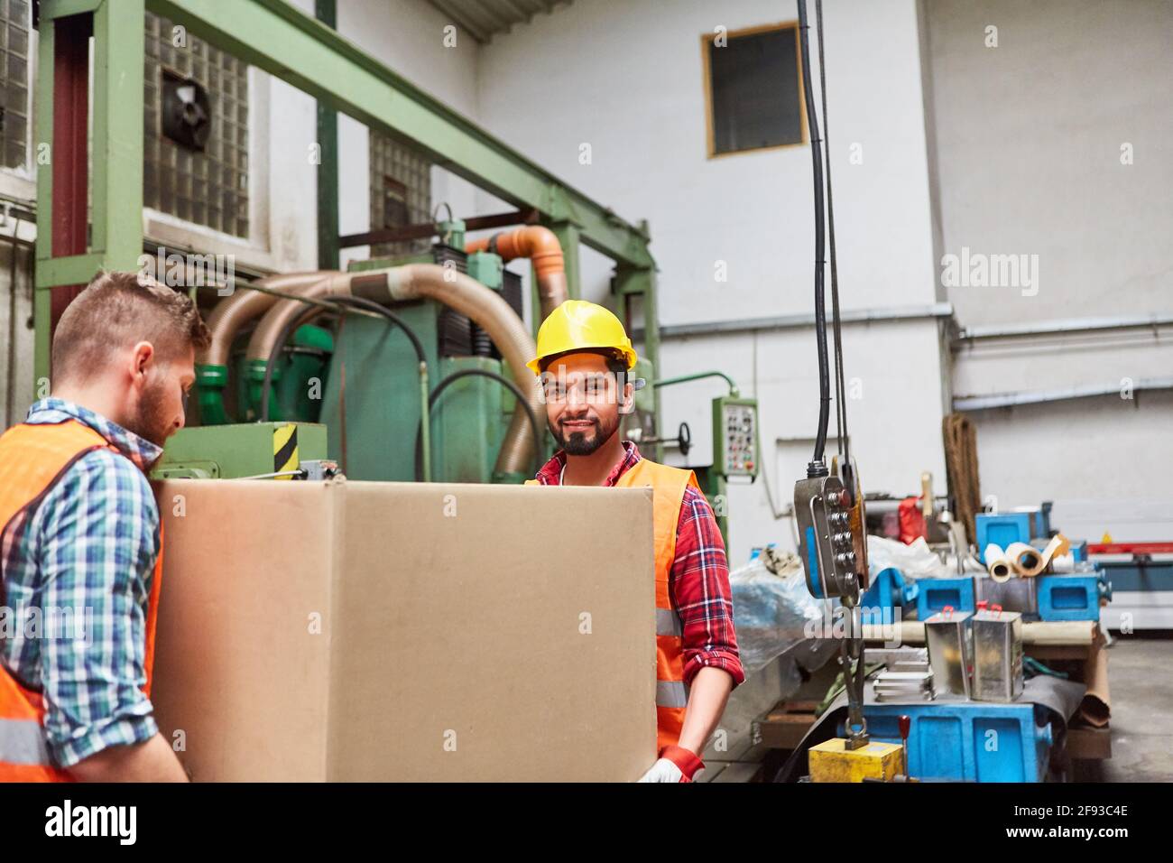 Warehouse workers carry a package together in the warehouse of the ...