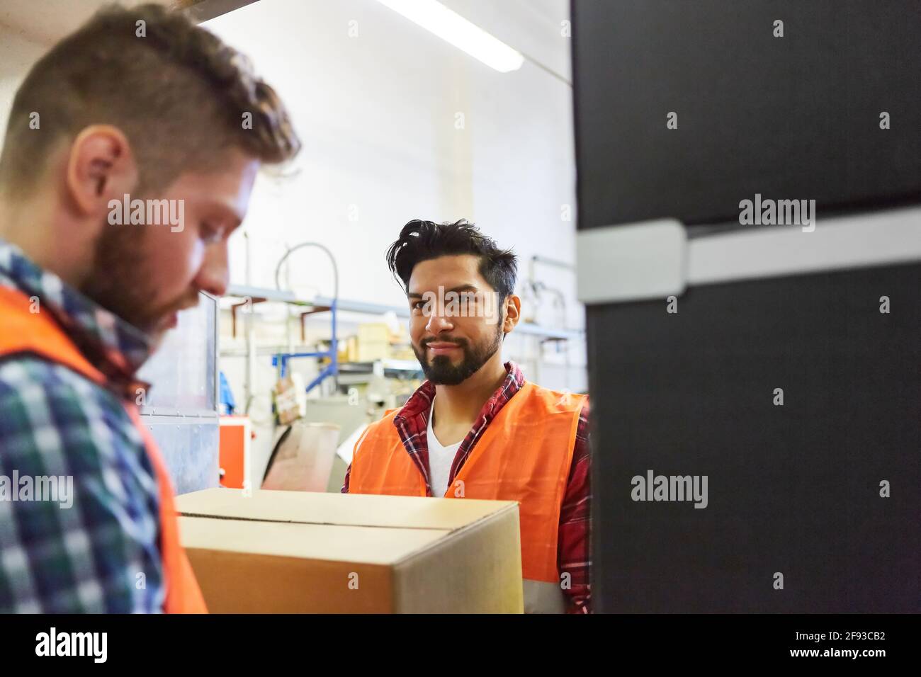 Two warehouse clerks with cardboard work together in receiving or ...
