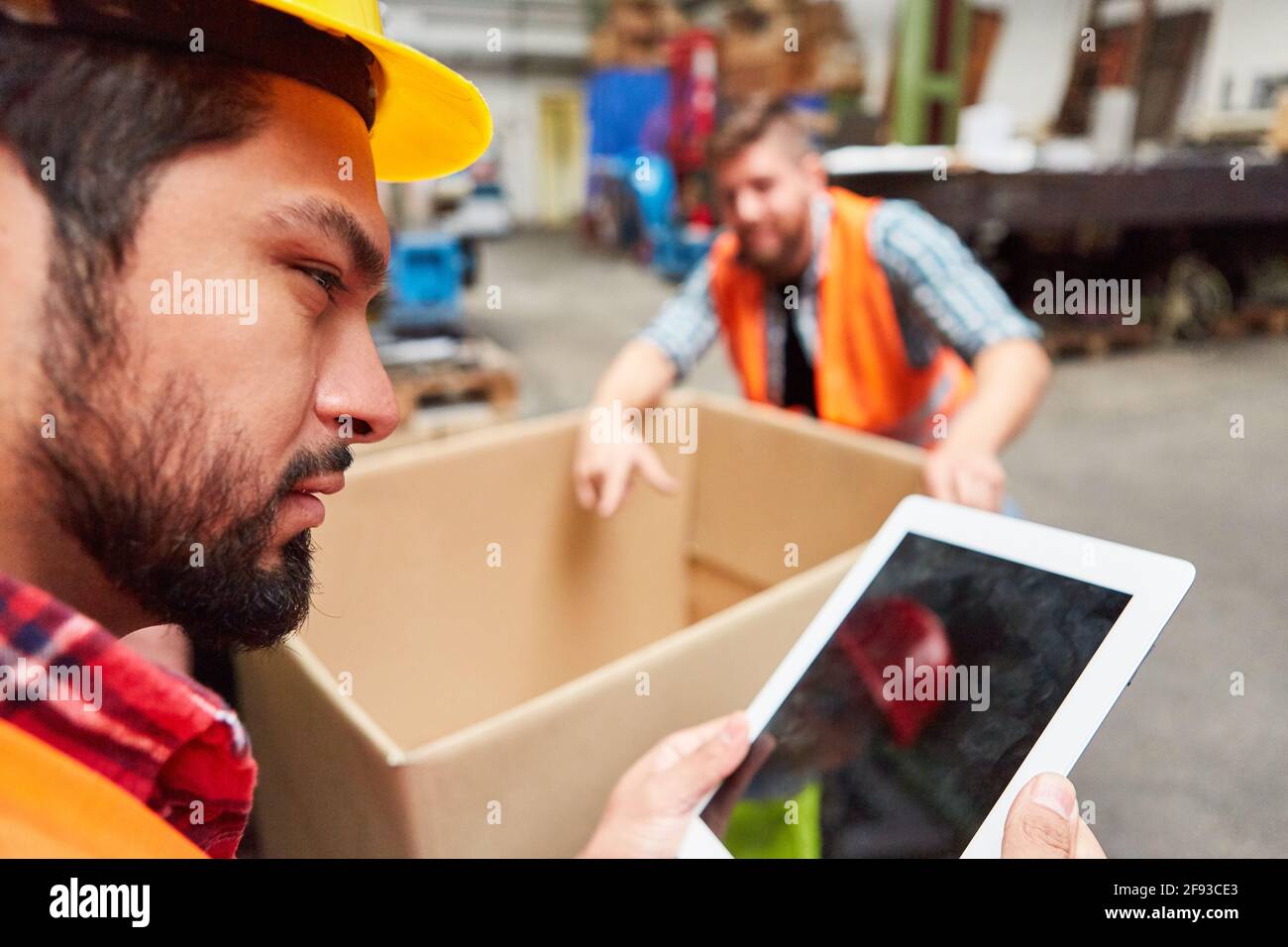Order picker checks incoming goods or order on the tablet computer in ...
