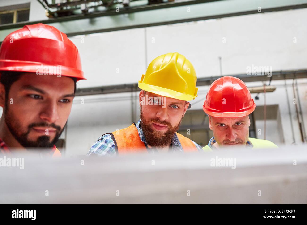 Three workers or craftsmen work together as a team in an industrial ...