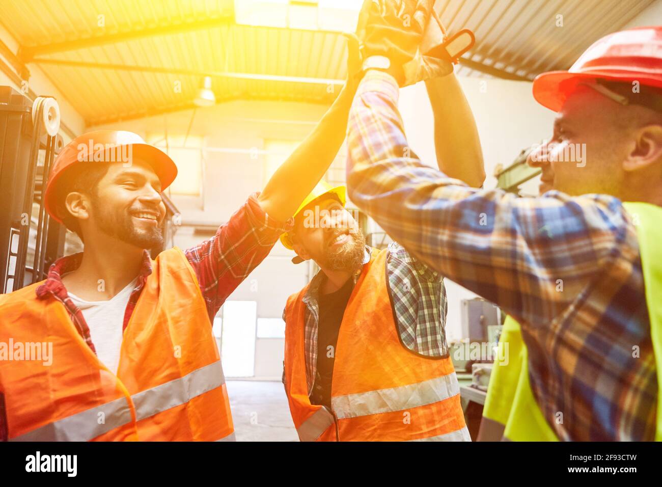 Workers in factory give high five for motivation as a sign of ...