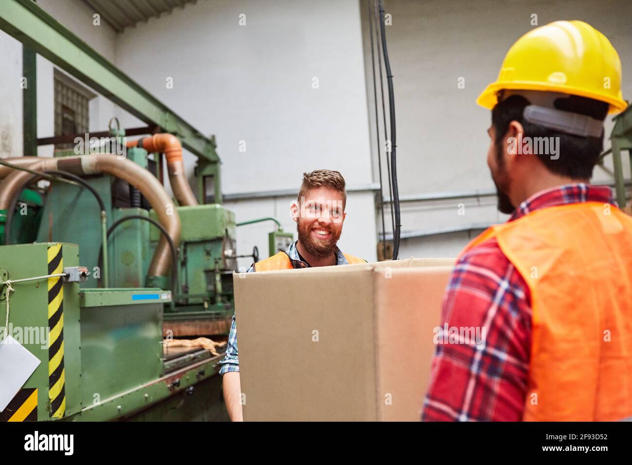 Warehouse workers carry cardboard boxes with a material delivery in the ...