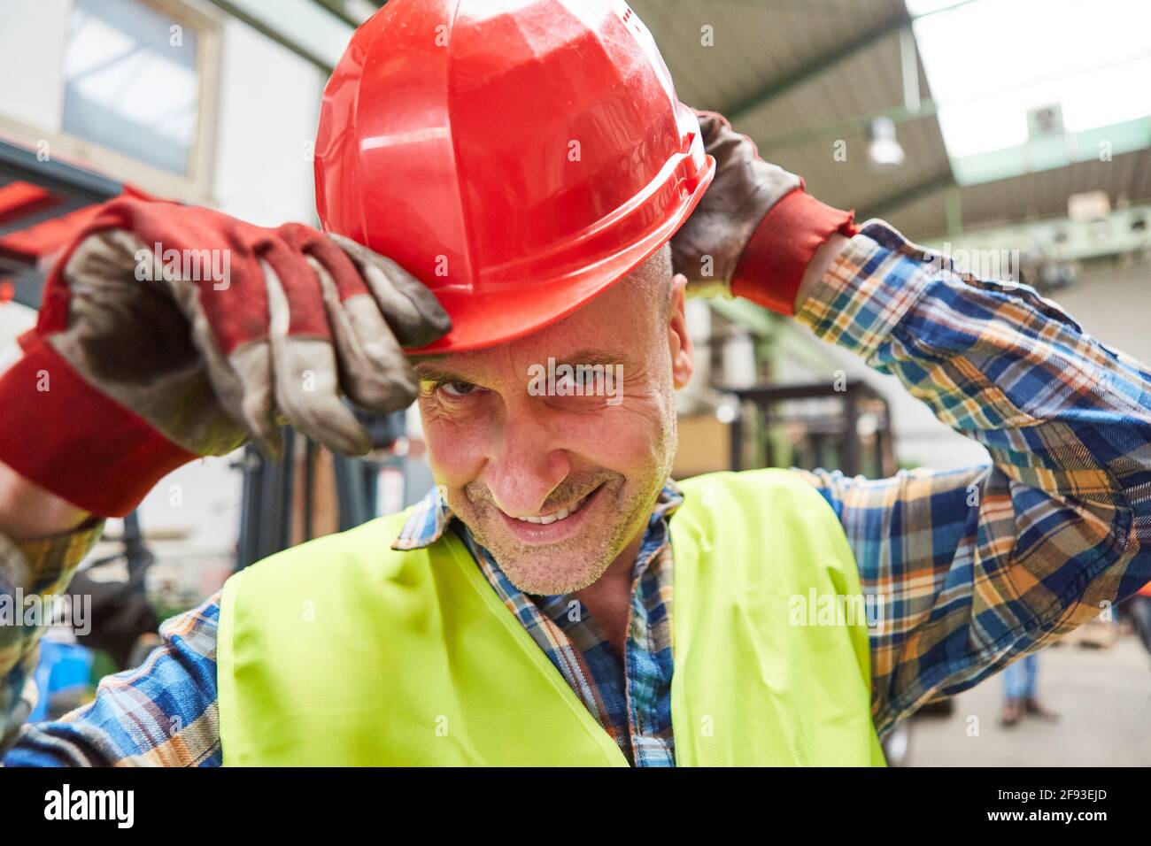 Smiling worker with red hard hat as a symbol for occupational safety ...