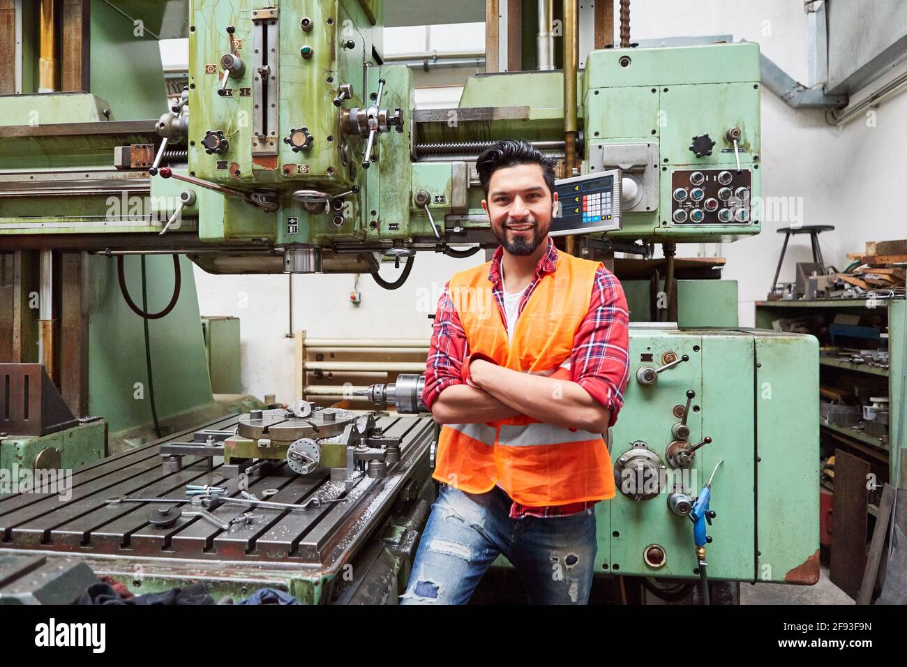 Proud metal worker with crossed arms in front of coordinate drilling ...
