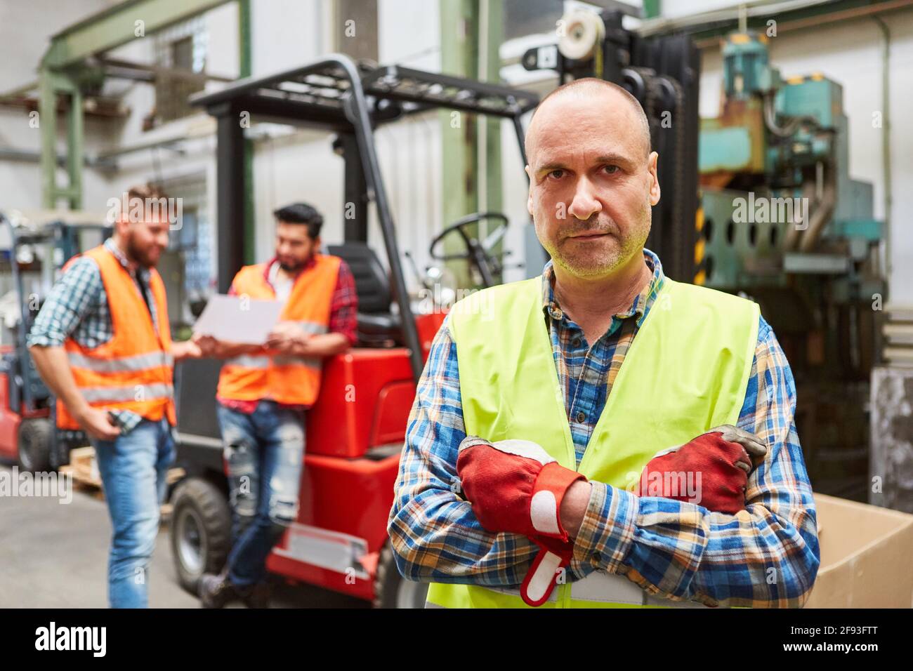 Warehouse worker as a forklift driver in front of a forklift in the ...