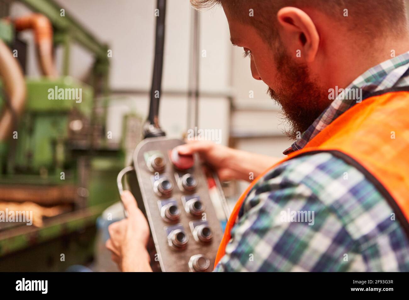 Worker as a machinist in the factory operates the buttons on the ...