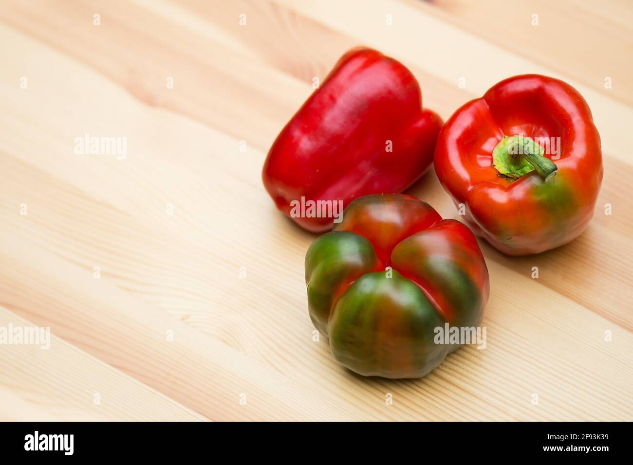 Red bell peppers on wooden table top angle Stock Photo - Alamy