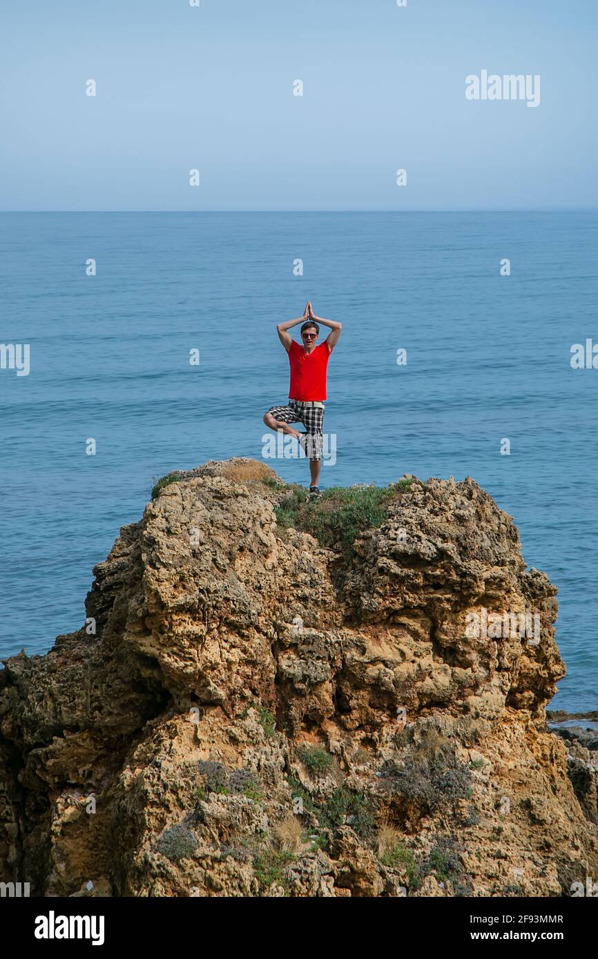 Full length portrait of a young man looking at sea waves from a rocky ...