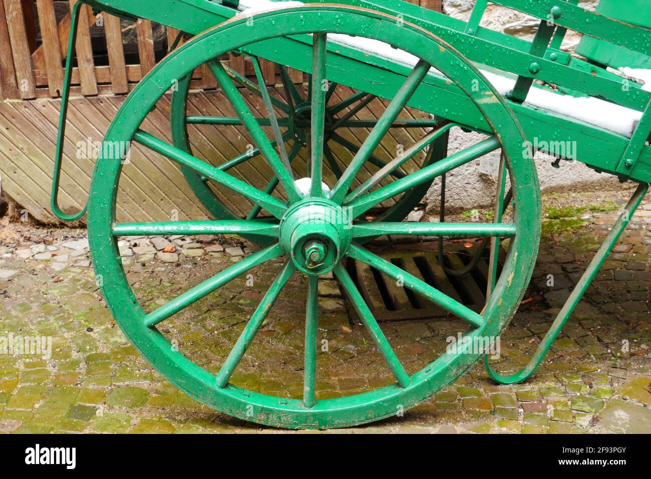 green old wagon wheel of a medieval handcart with snow on the cart ...