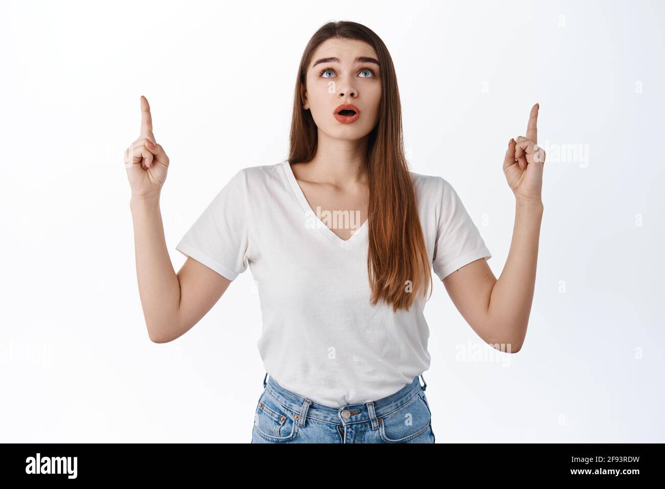 Intrigued beautiful girl with long hair, gasping fascinated, pointing ...