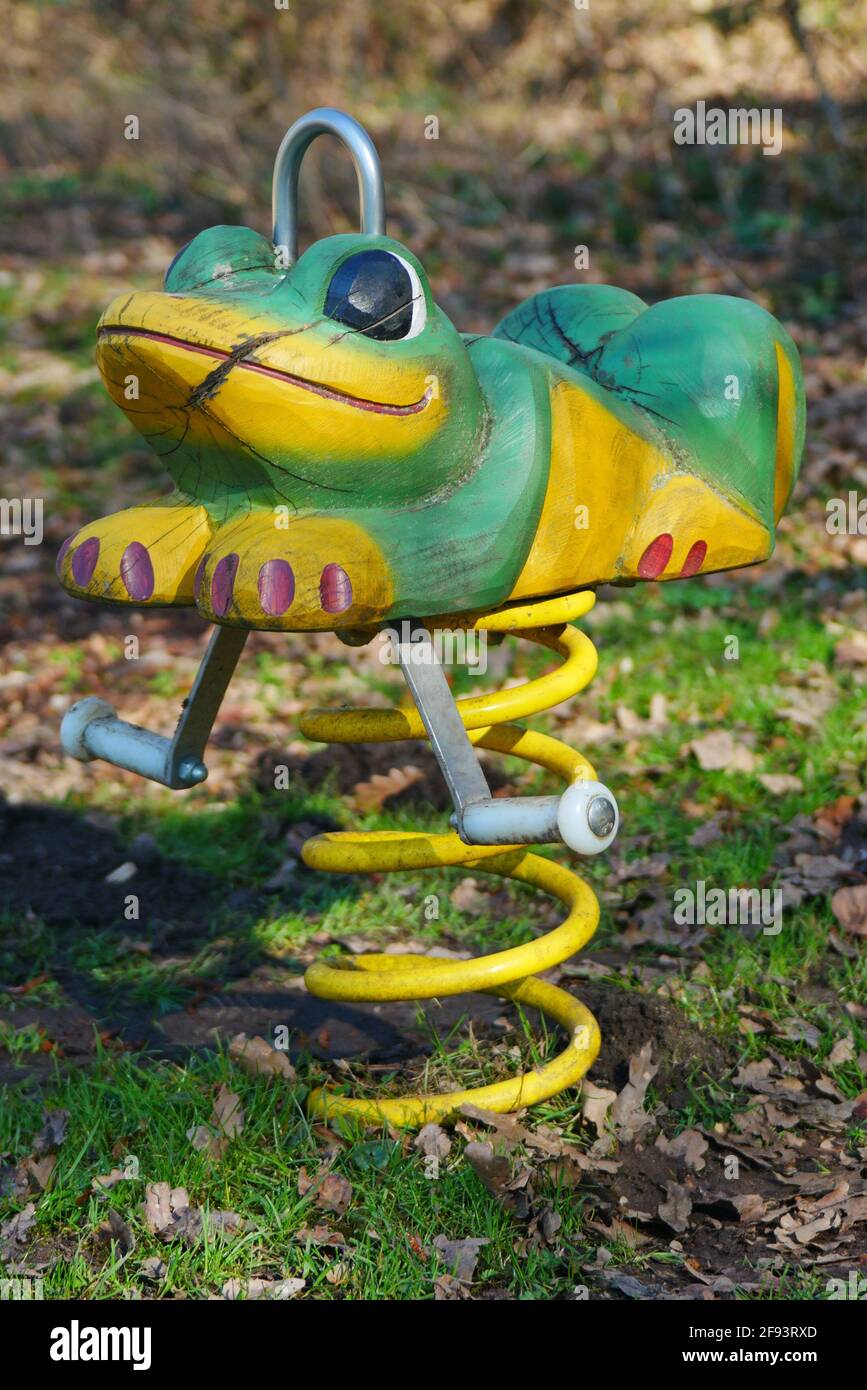 old wooden seesaw on a playground in the form of a green yellow frog ...