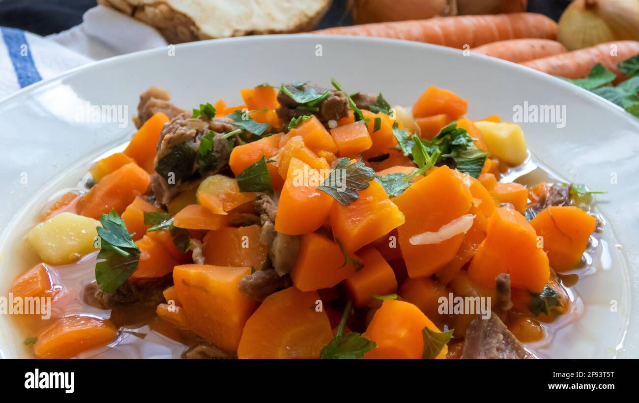 Closeup of a delicious carrot stew with beef served on a white plate ...