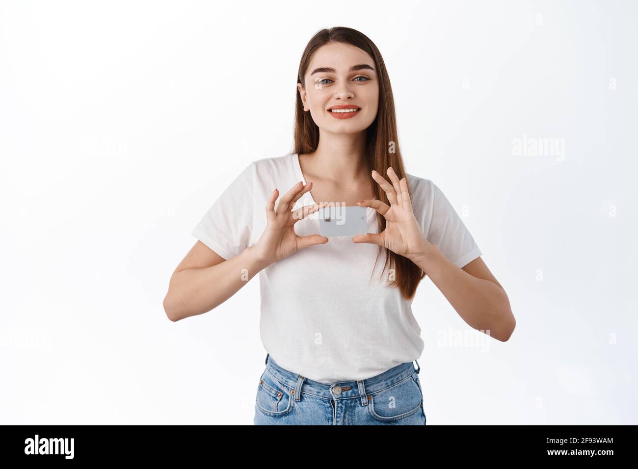 Smiling cute girl bank client, holding credit card with both hands near ...