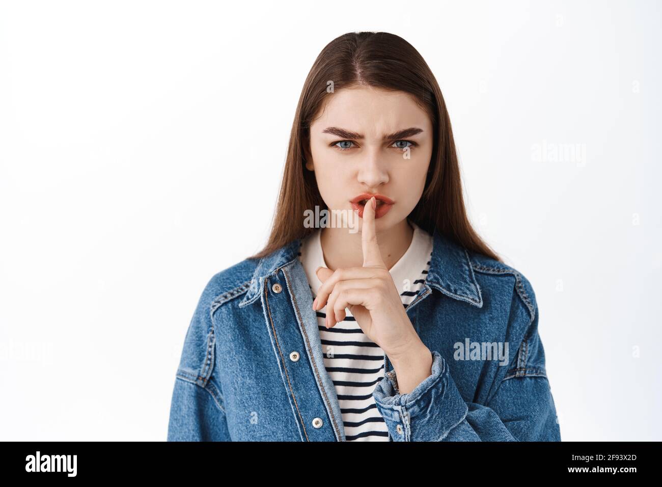 Angry young woman shushing, frowning and make shhh hush gesture with ...
