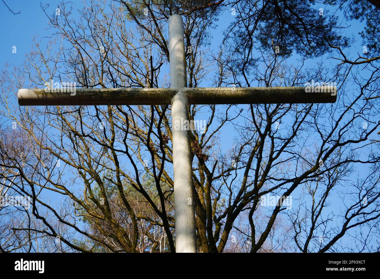 old christian stone cross in the light and shadow in the treetops with ...